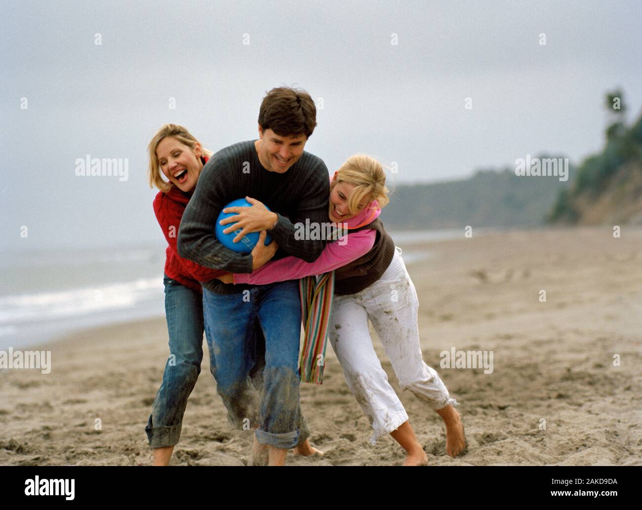 Three friends playing with ball at the beach Stock Photo - Alamy