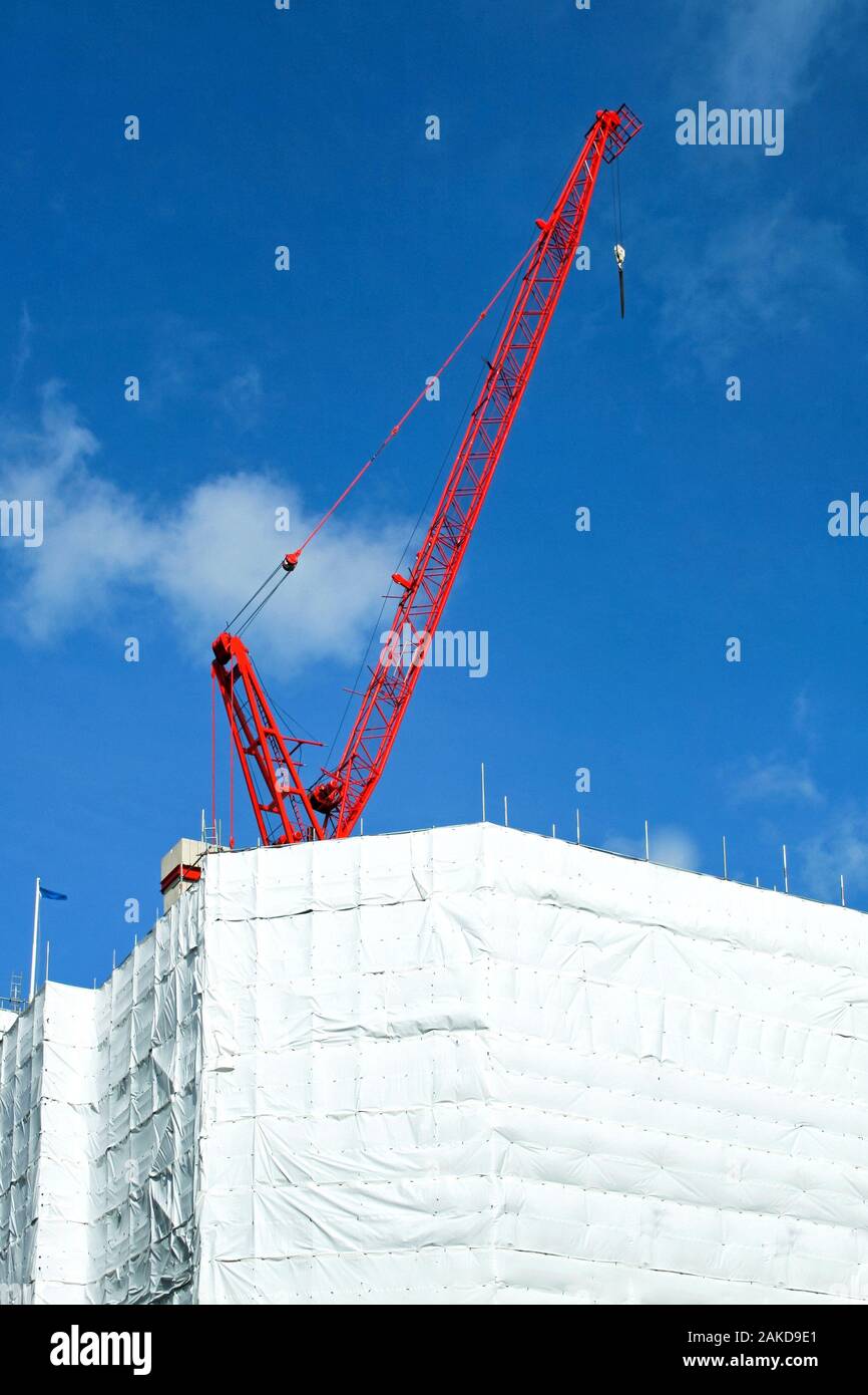 Big red construction crane on top of building Stock Photo - Alamy