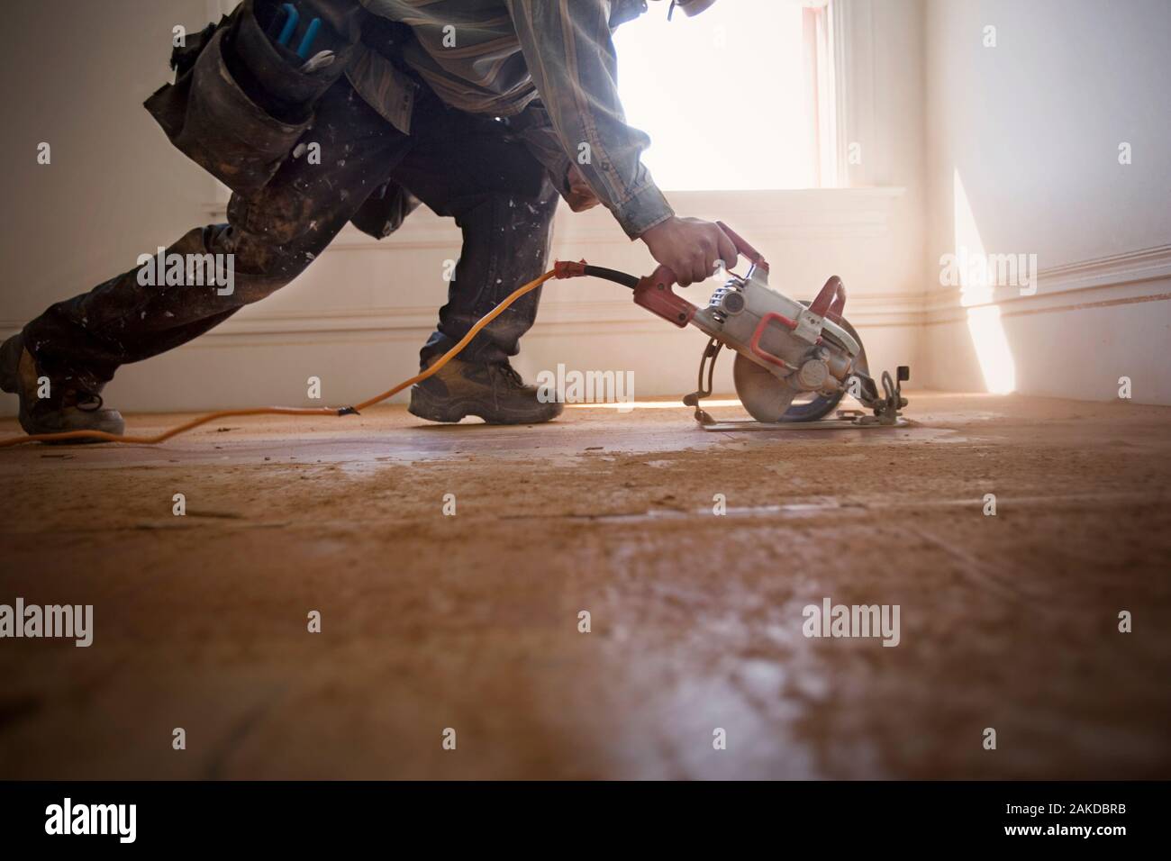 Male builder sanding floorboards with a power tool inside a room Stock ...