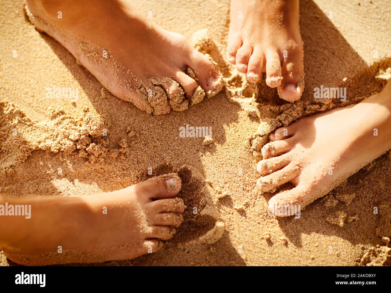 Close up of four feet on the sand Stock Photo - Alamy
