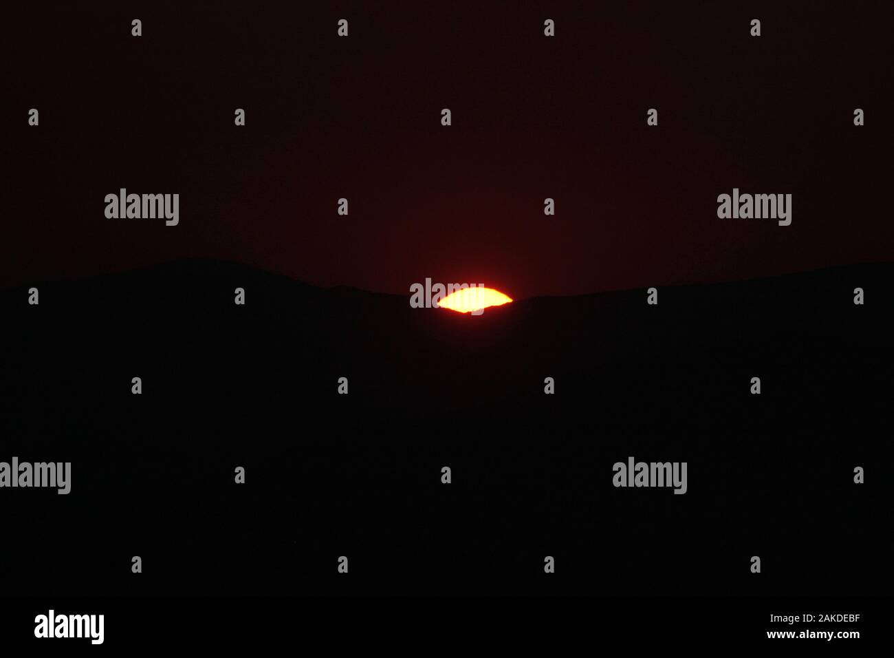 Sun disappearing behind the hills at night Stock Photo - Alamy