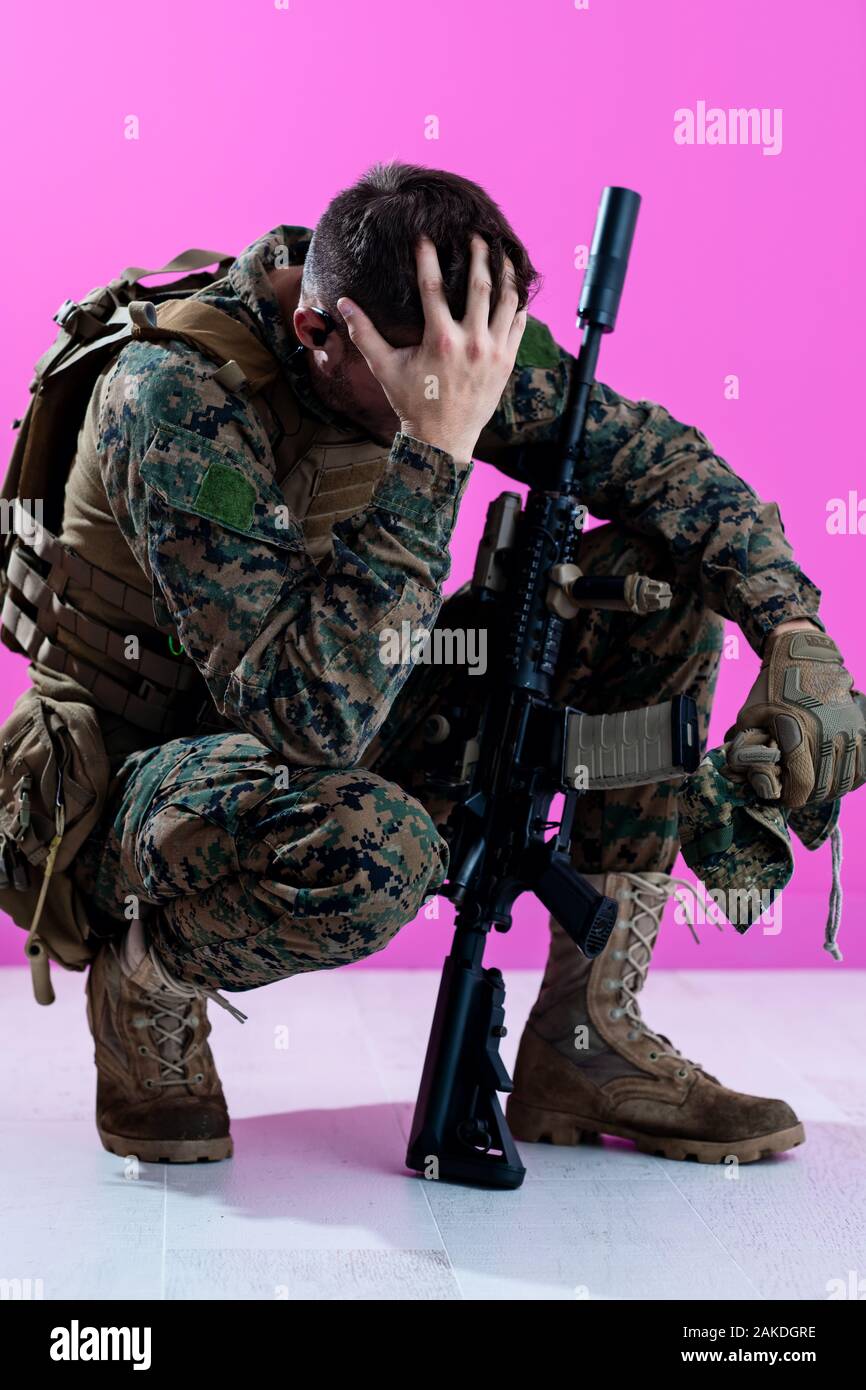 sad soldier has psychological problems holding his head in a squatting ...