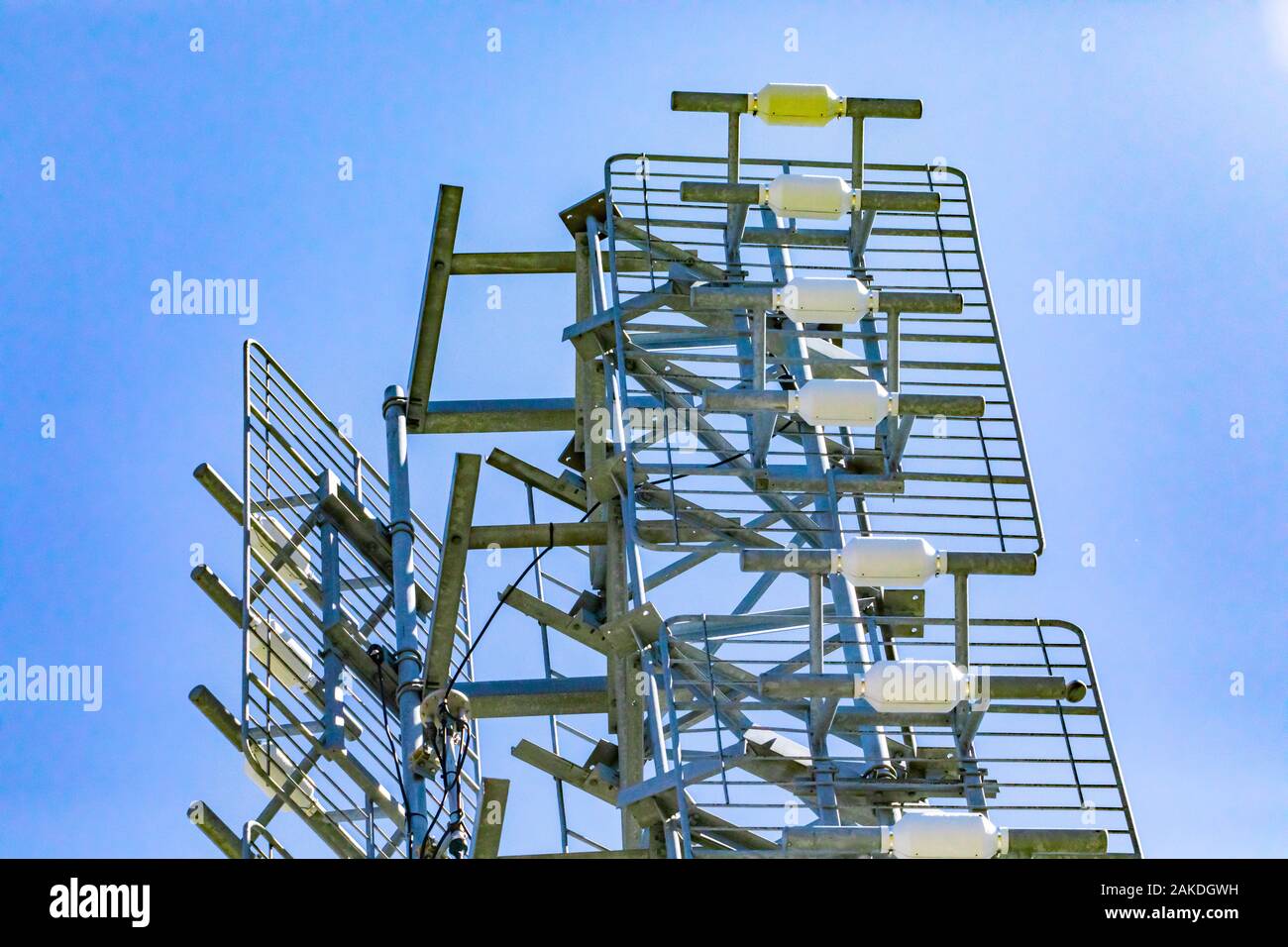 A low angle view of a cell site tower housing multiple antenna. Radio ...