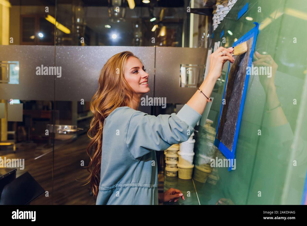 Nice colours. Content young woman holding a brush and picking a colour ...