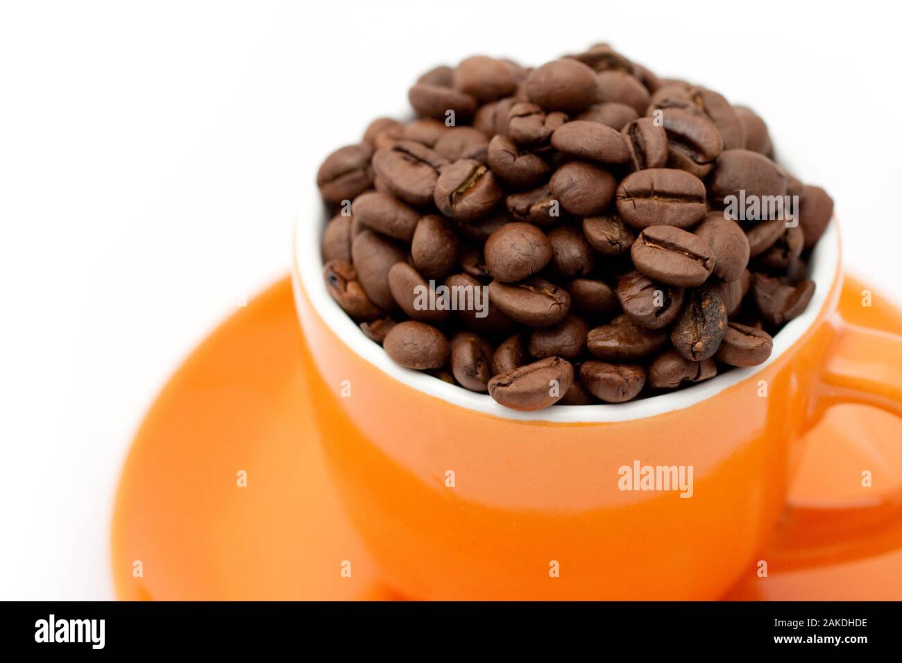Roasted coffee beans in an orange cup isolated on white background ...