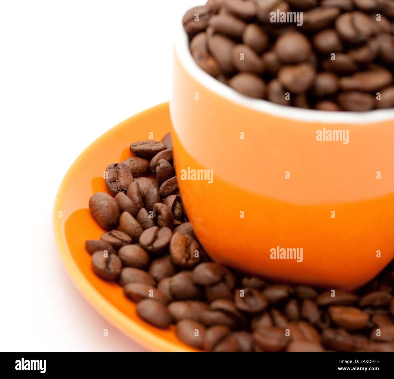 Roasted coffee beans in an orange cup isolated on white background ...