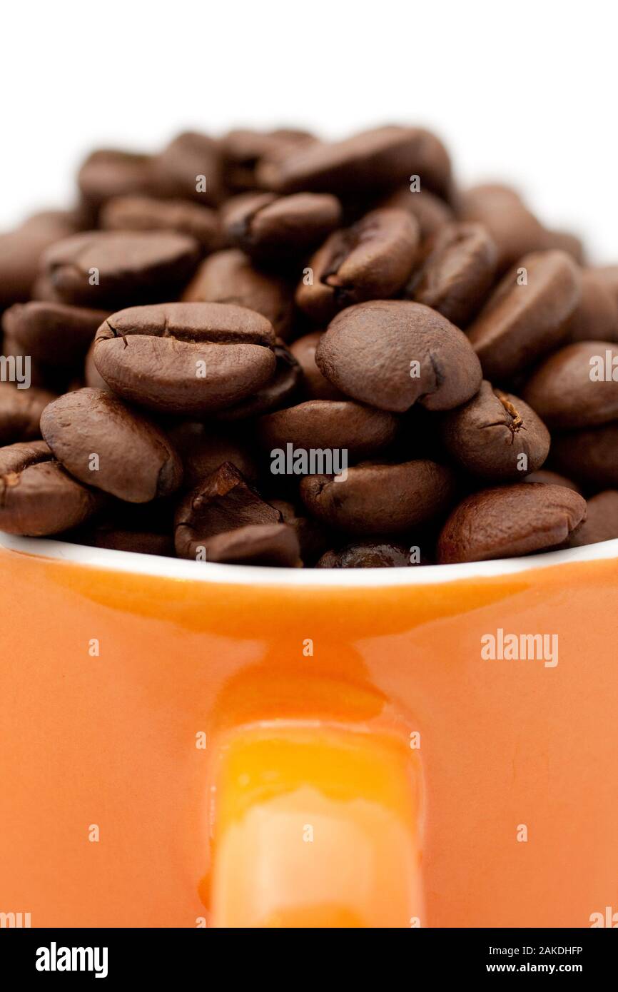 Roasted coffee beans in an orange cup isolated on white background ...