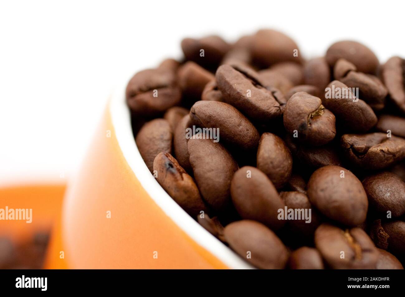Roasted coffee beans in an orange cup isolated on white background ...