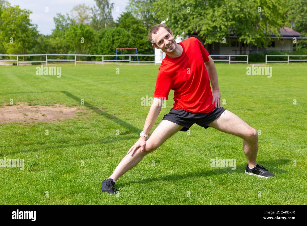 Young handsome sportsman is doing stretching exercises before workout ...