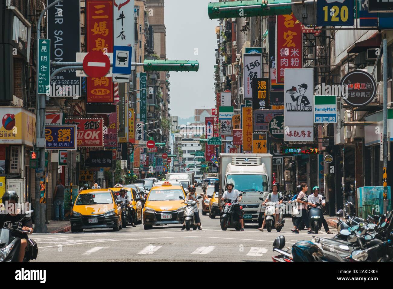Scooters and taxis wait at the front of the traffic lights at an inner ...