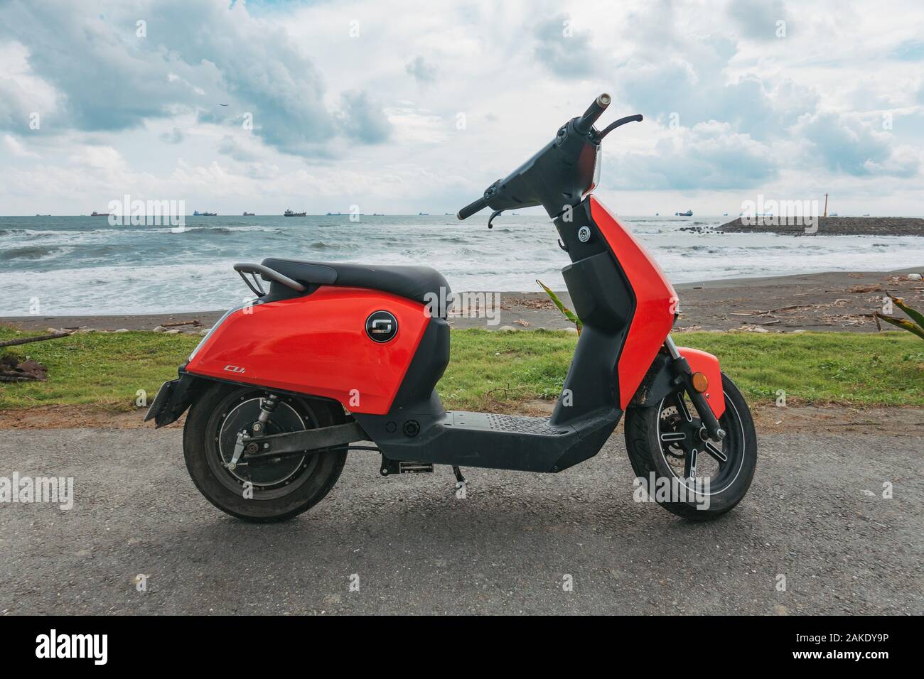 A red Super Soco CU e-scooter parked on a path in Qijin Coastal Park ...