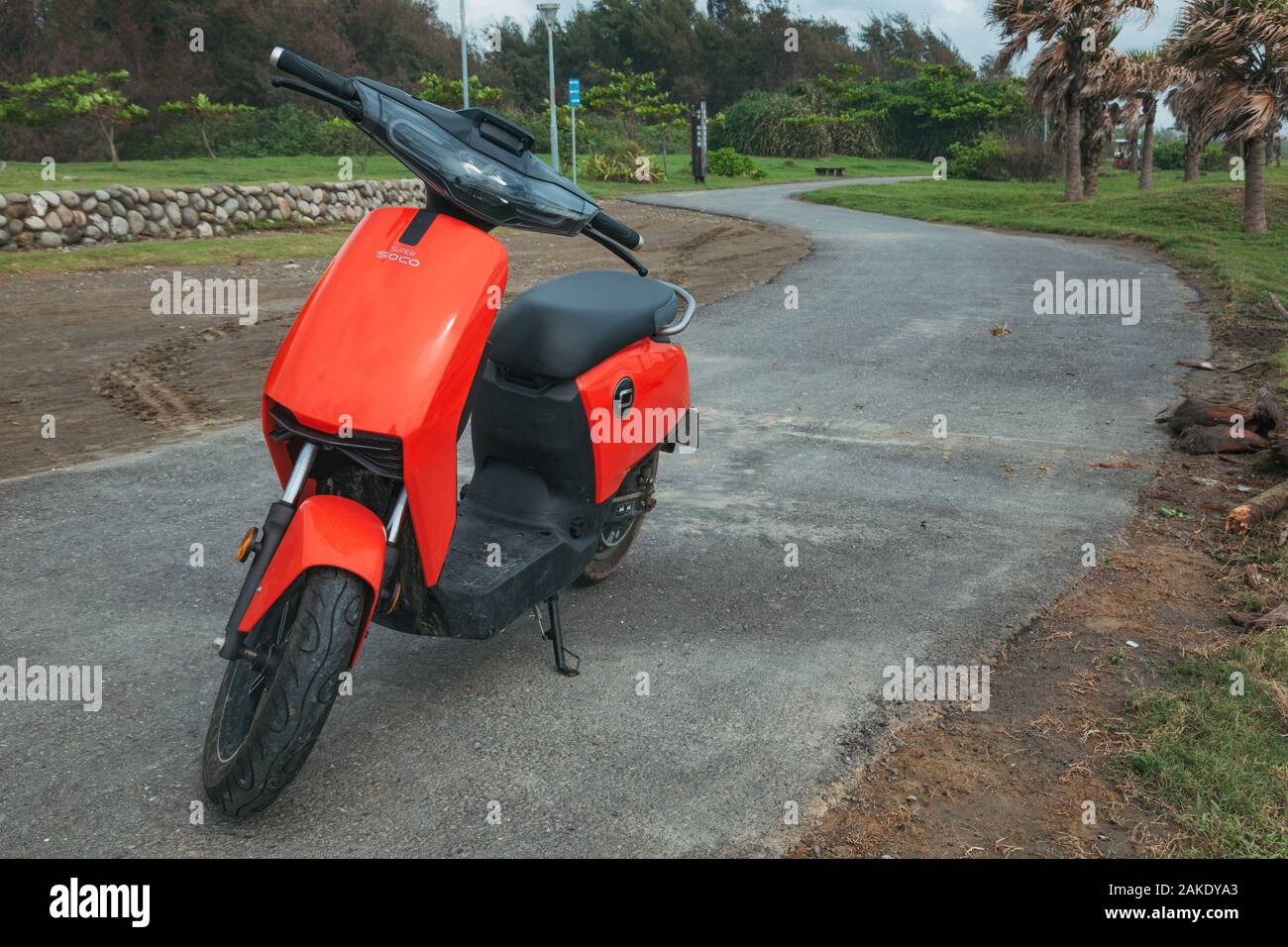 A red Super Soco CU e-scooter parked on a path in Qijin Coastal Park ...