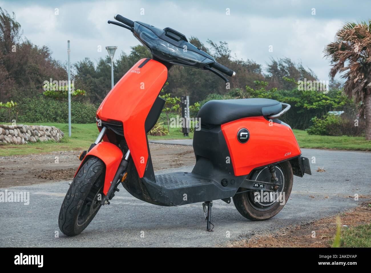 A red Super Soco CU e-scooter parked on a path in Qijin Coastal Park ...