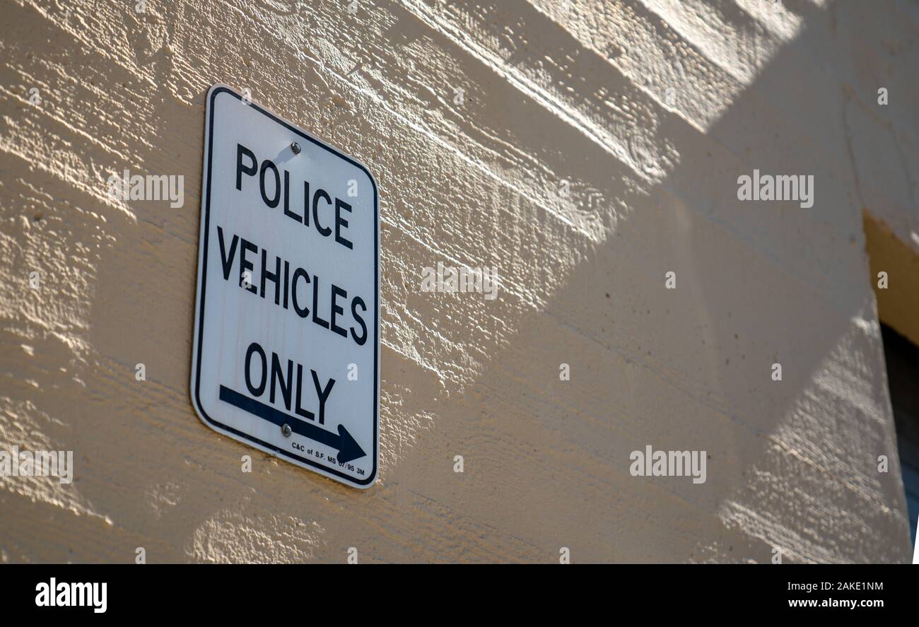 Police vehicles only with arrow pointing right sign hanging on building ...