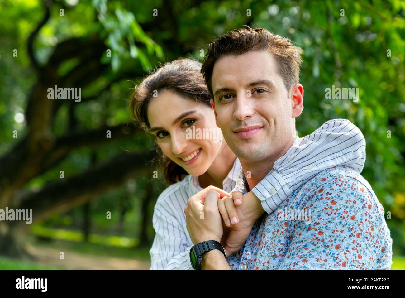 portrait smiling young man and woman couple in love hugging in the park ...