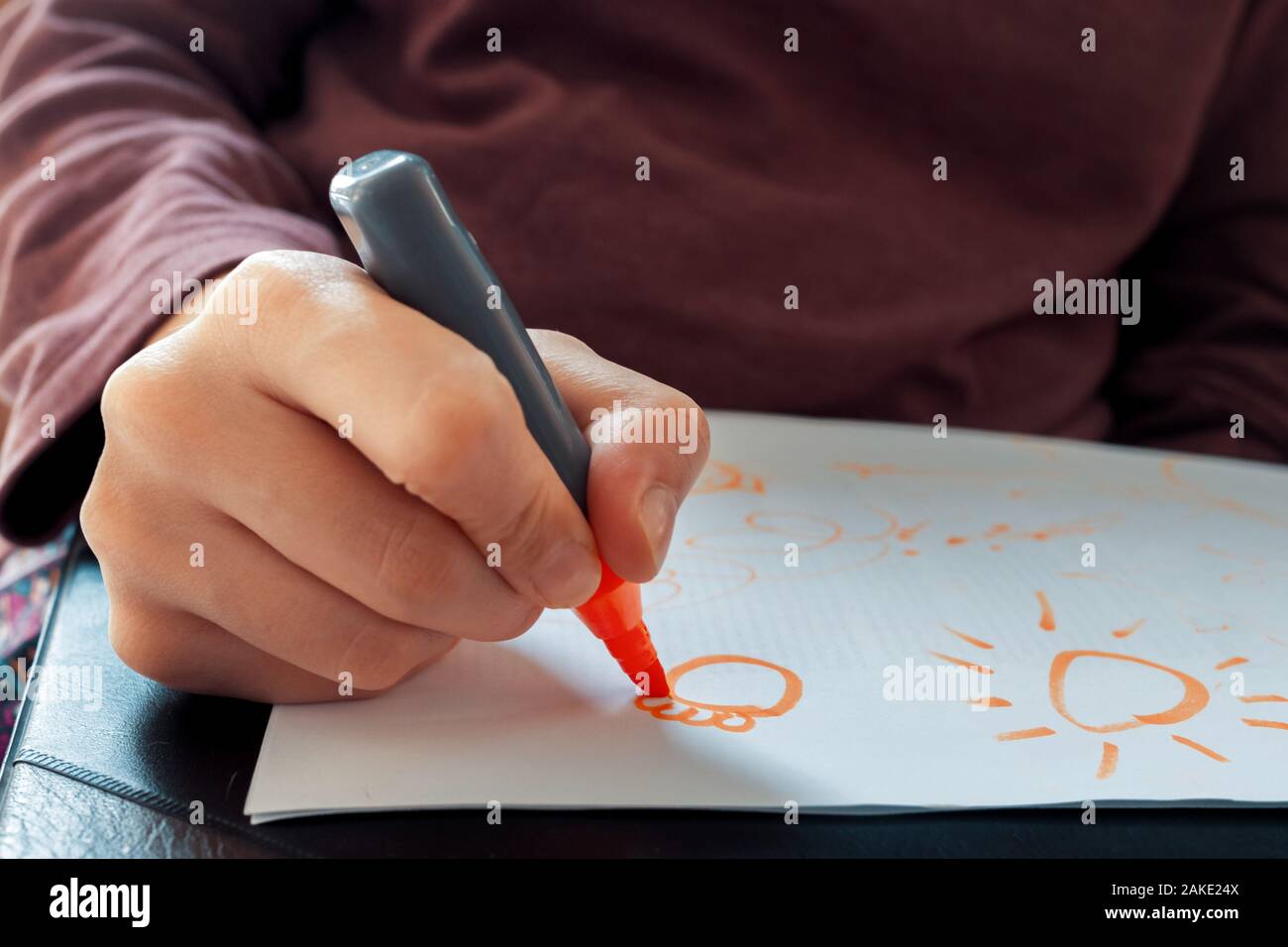young teenager using an orange color highlighter pen to drawing flower ...