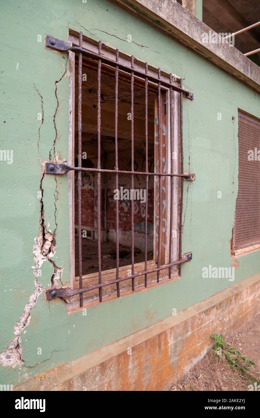 Rusted steel gate blocking window in dilapidated building with concrete ...