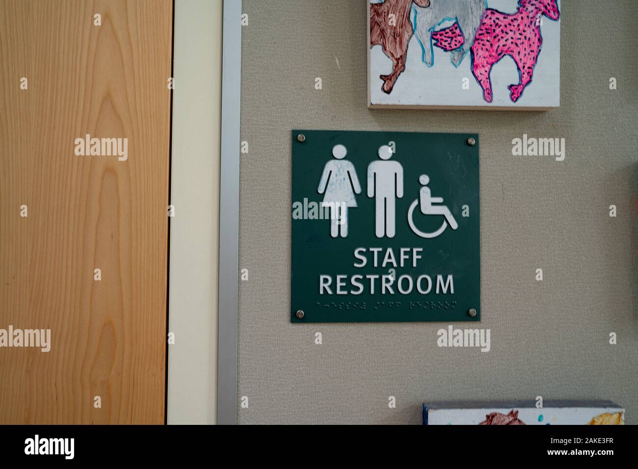 Green staff restroom sign with woman, man, and wheelchair symbol Stock ...