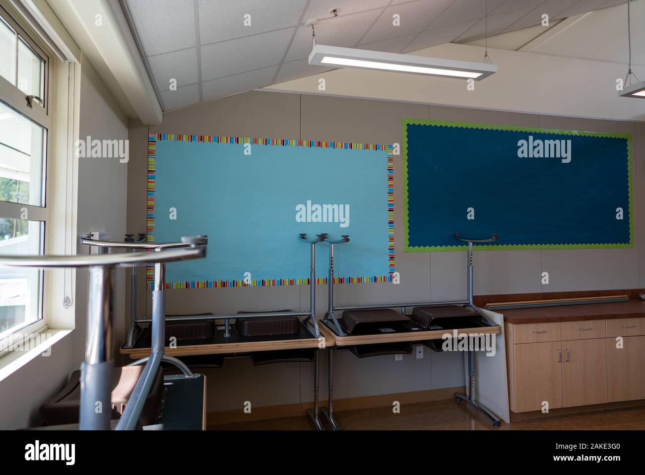 Corner of empty classroom with tables and blank posters before school ...