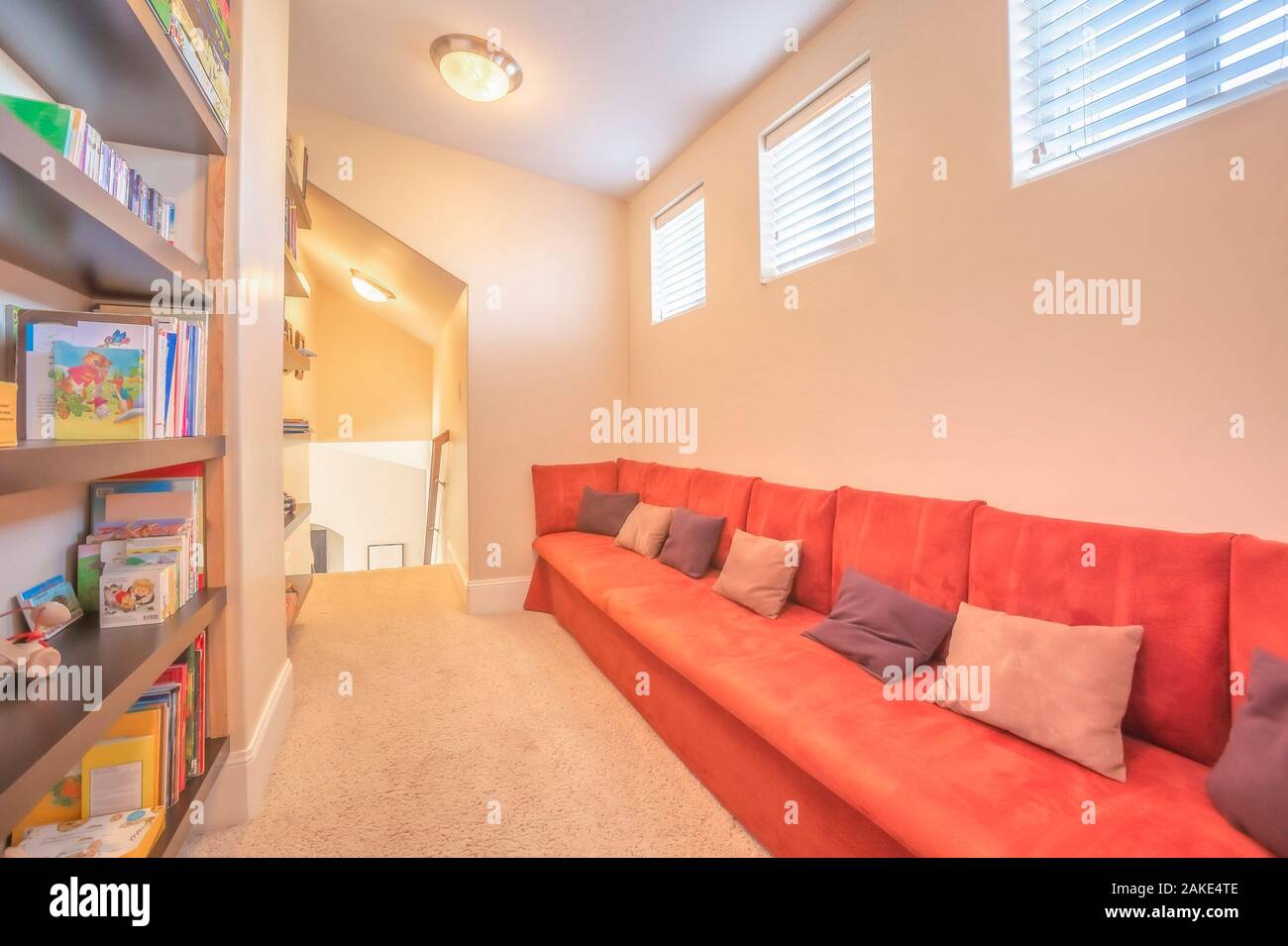 Reading room interior with long red couch in front of wall shelves with ...