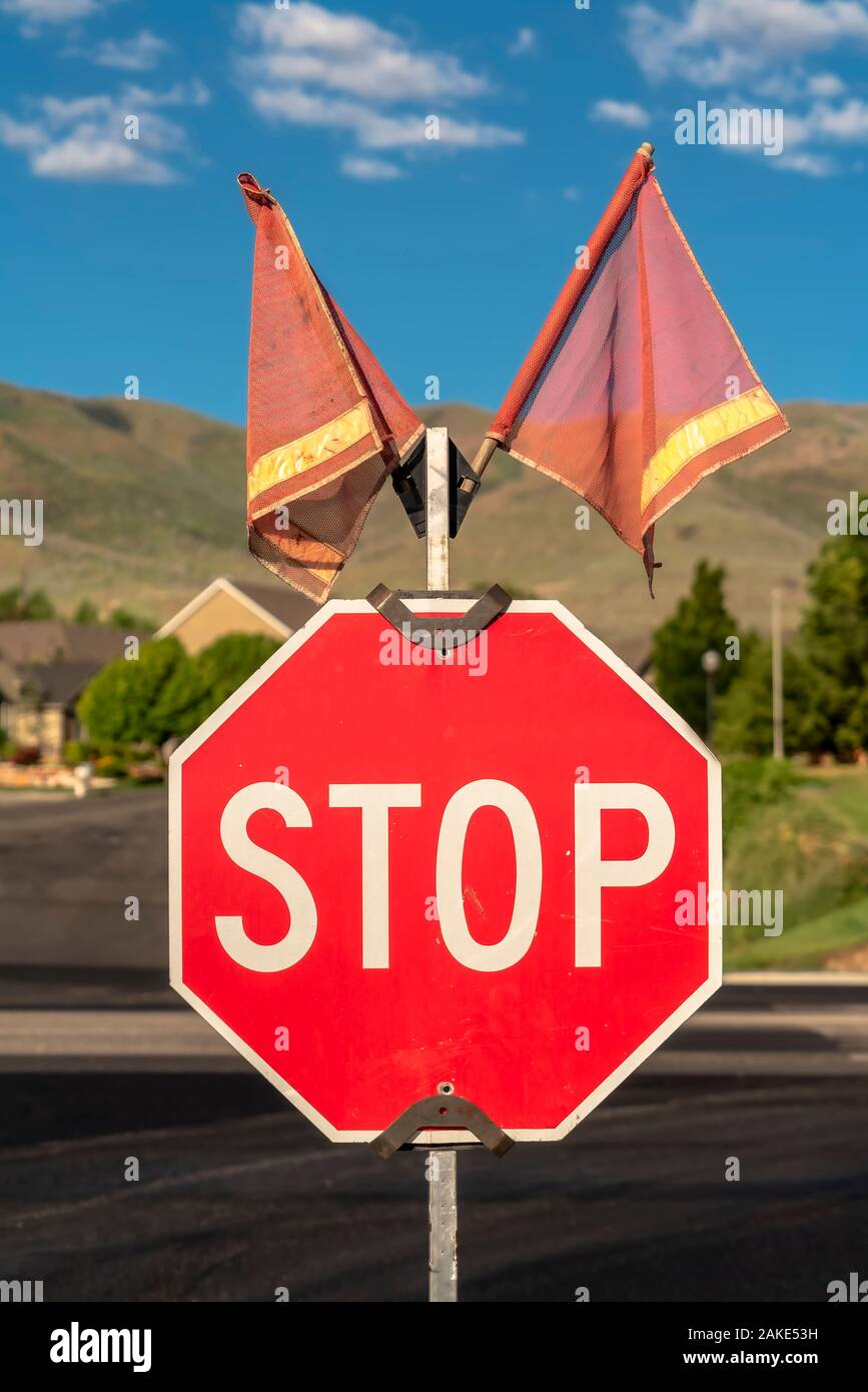 Selective focus of traffic Stop sign with two red flags against road ...
