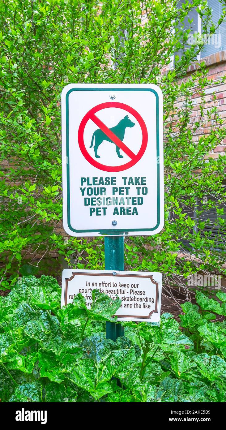Vertical frame Focus on a pet sign outside a building against leaves ...