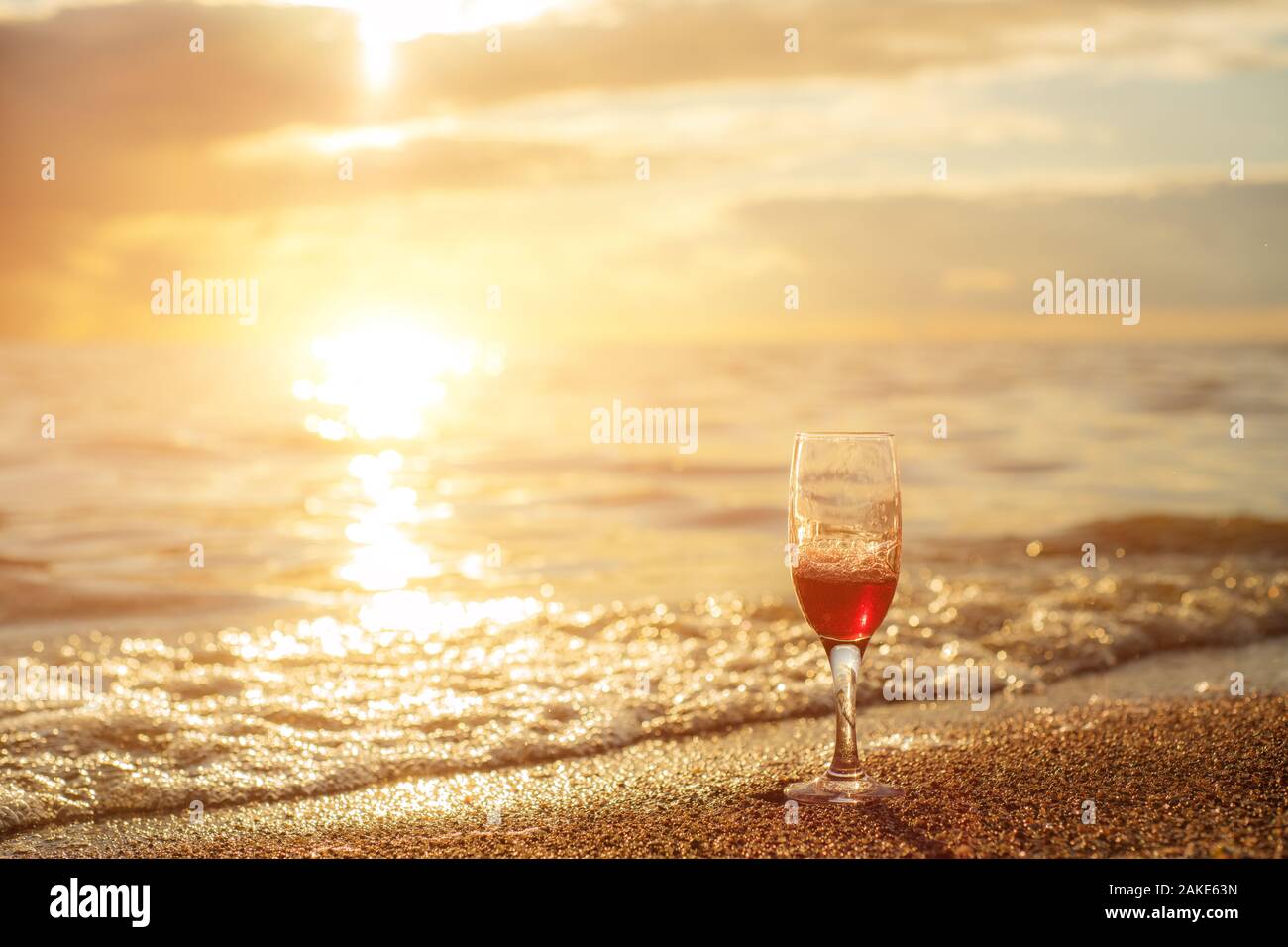 Romantic beach scene: glass of red wine at sunset near water line Stock ...