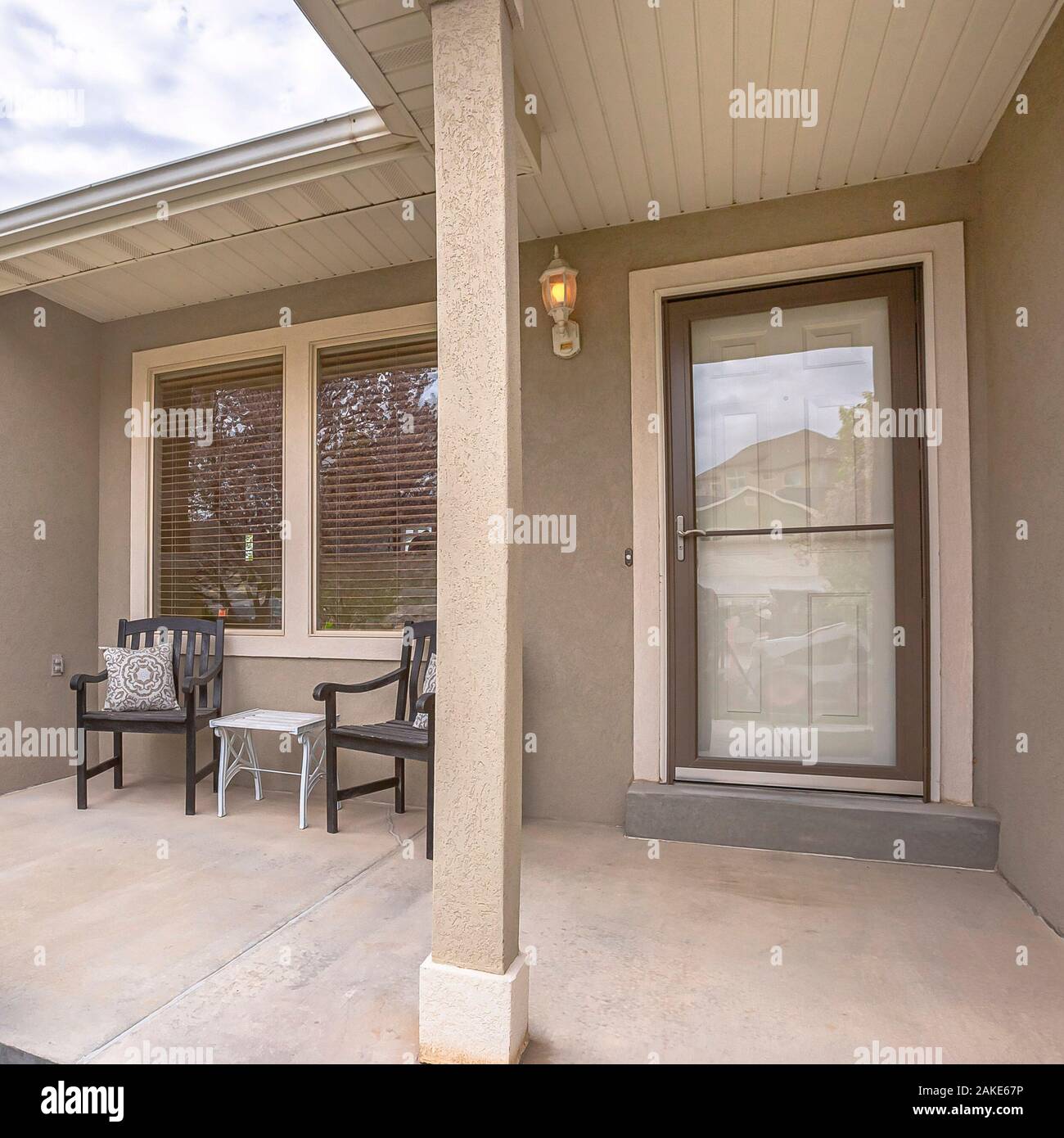 Square frame Chairs and table at the concrete porch of a home with bay ...