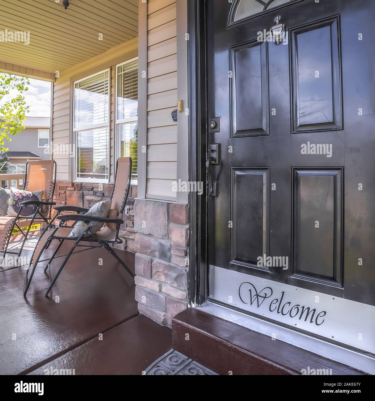 Square frame Front door of house with glass panes and porch with chairs ...