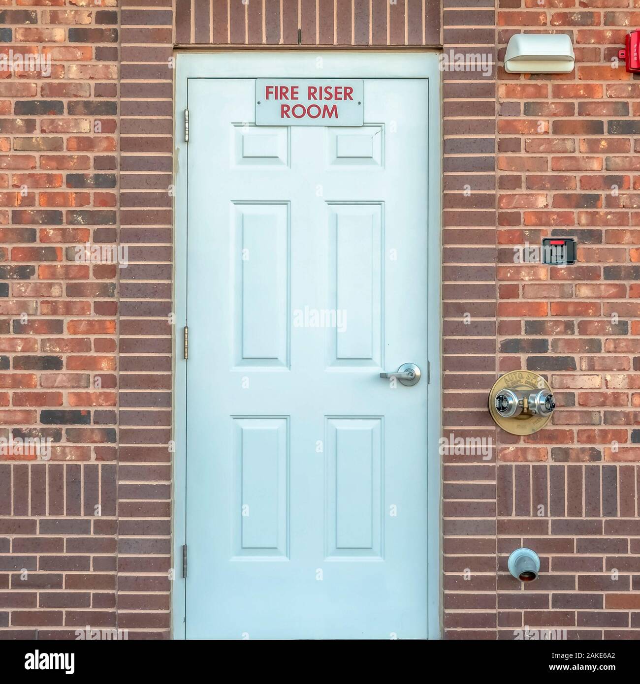 Square Fire Riser Room sign on the white wood door of a building with ...