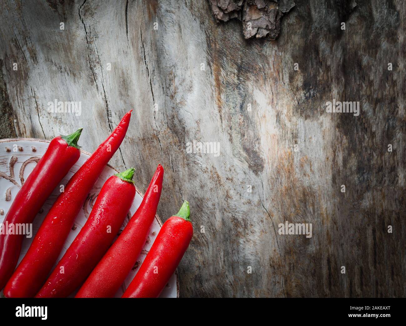 Red chillies on aged wood background. Vintage plate Stock Photo - Alamy