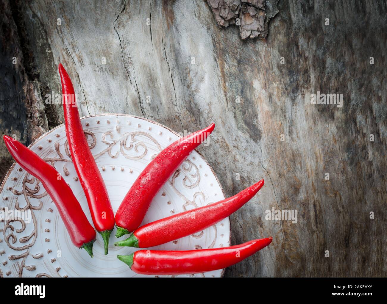 Red chillies on aged wood background. Vintage plate Stock Photo - Alamy