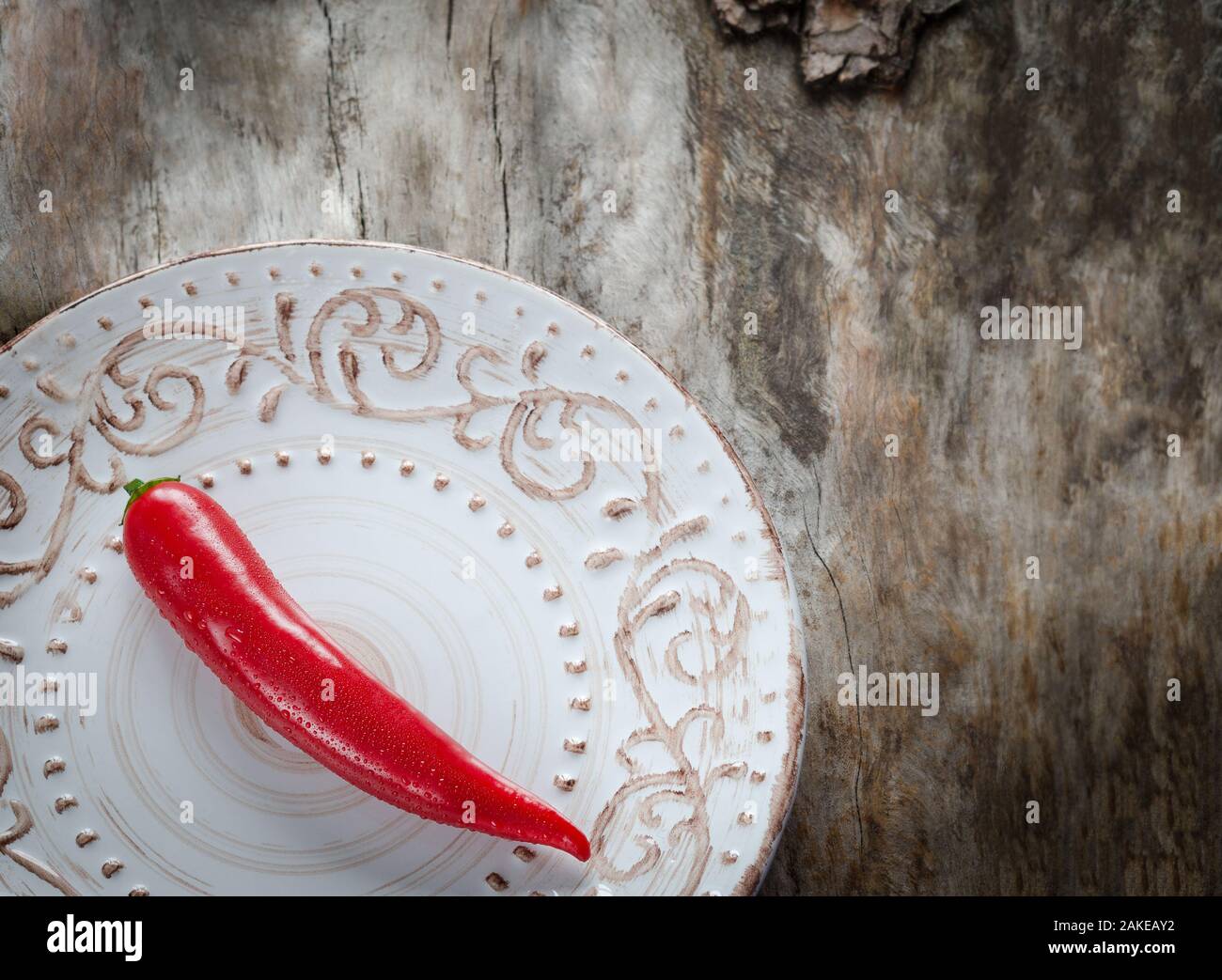 Red chilli on aged wood background. Vintage plate Stock Photo - Alamy