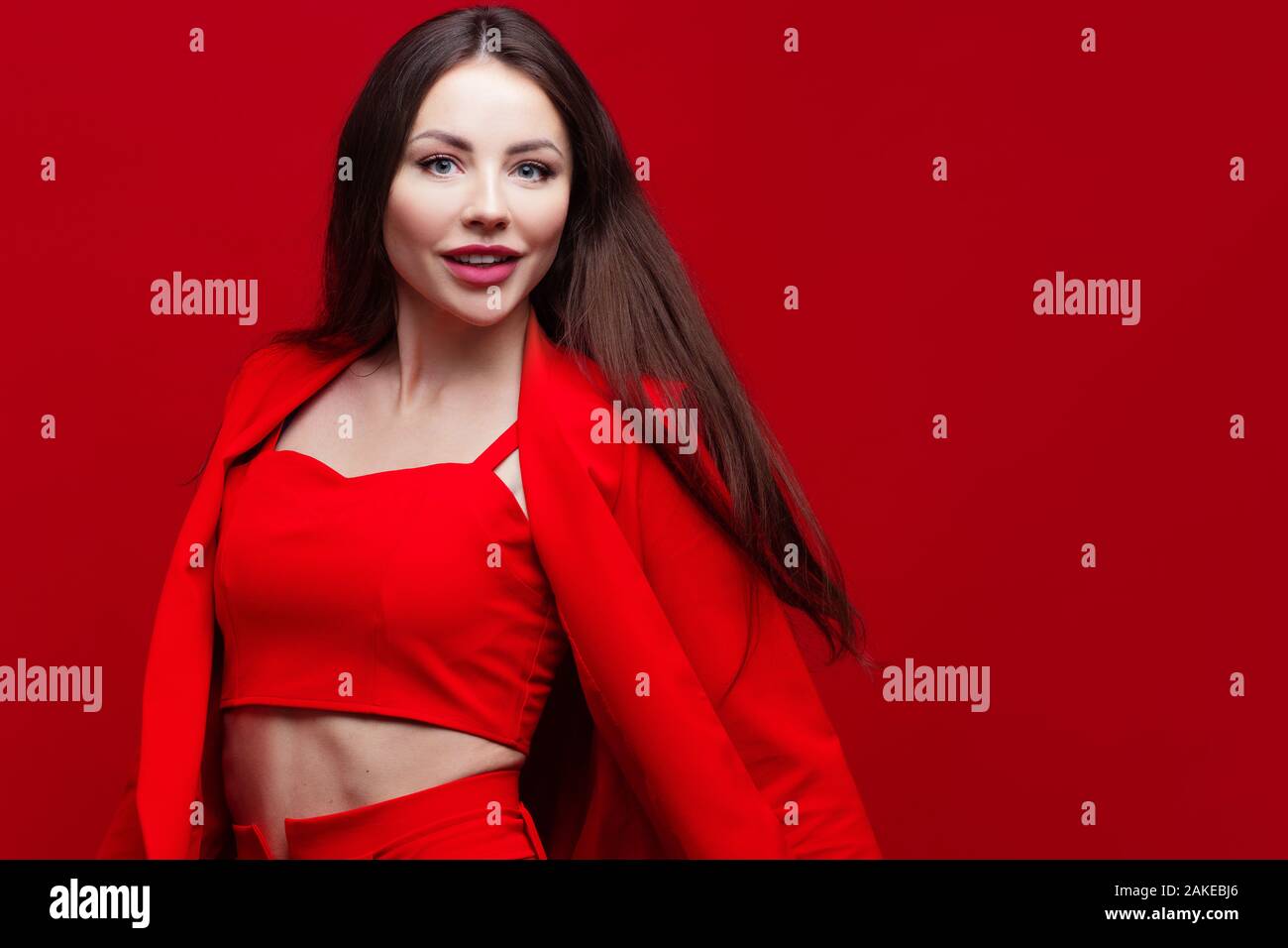 Stylish young woman in a red suit on a red background. One-color image ...