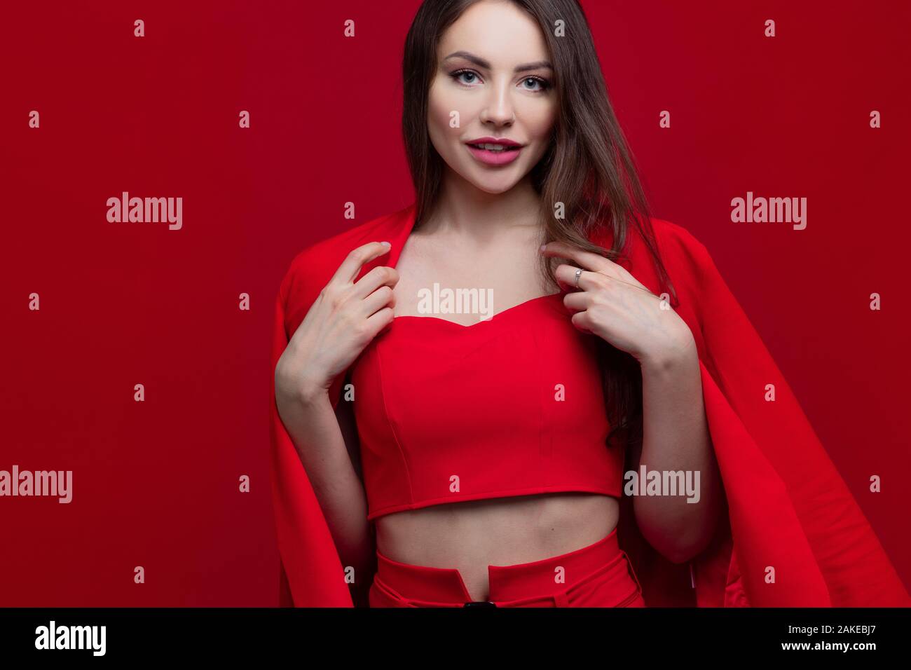 Stylish young woman in a red suit on a red background. One-color image ...