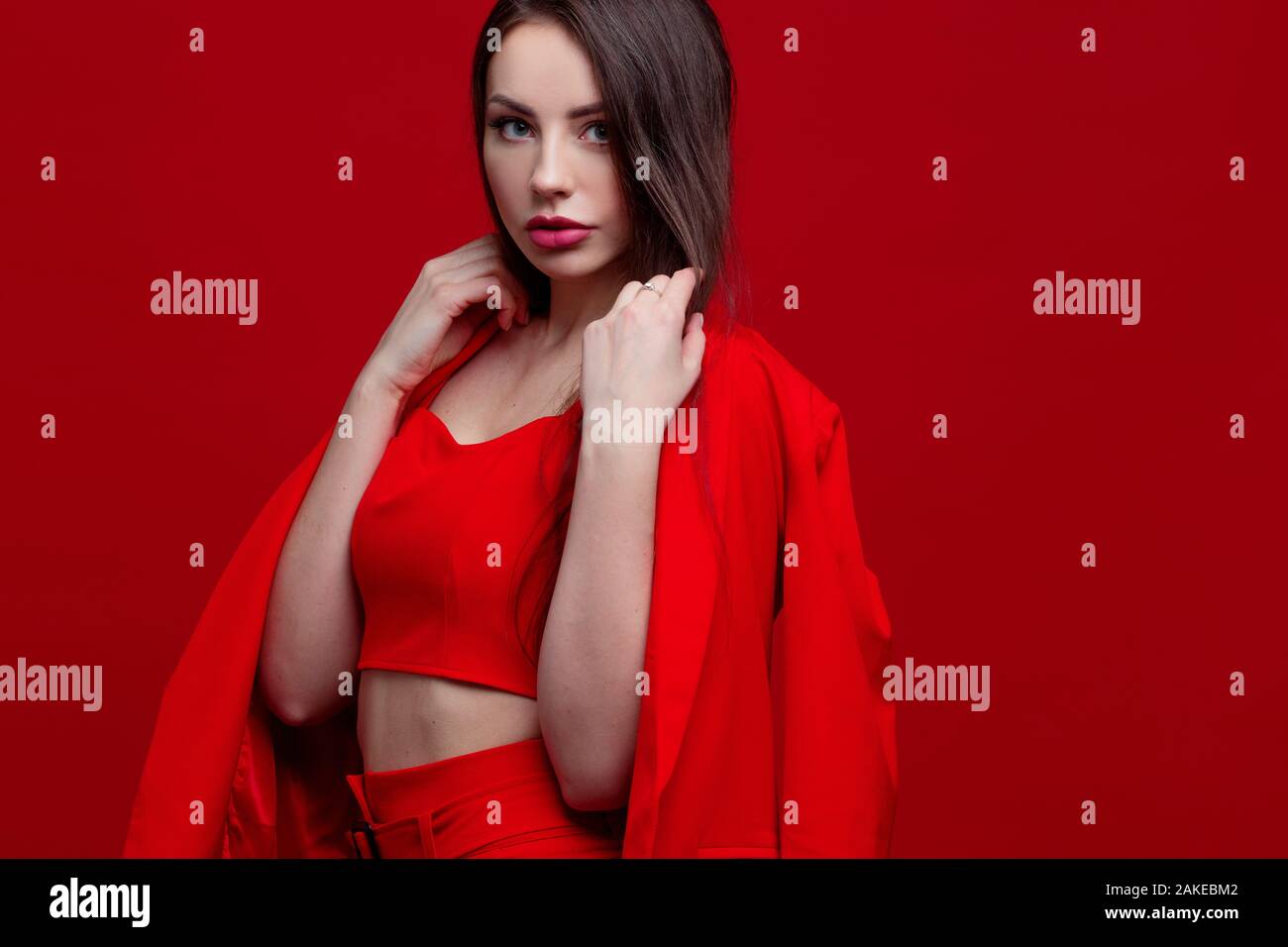 Stylish young woman in a red suit on a red background. One-color image ...