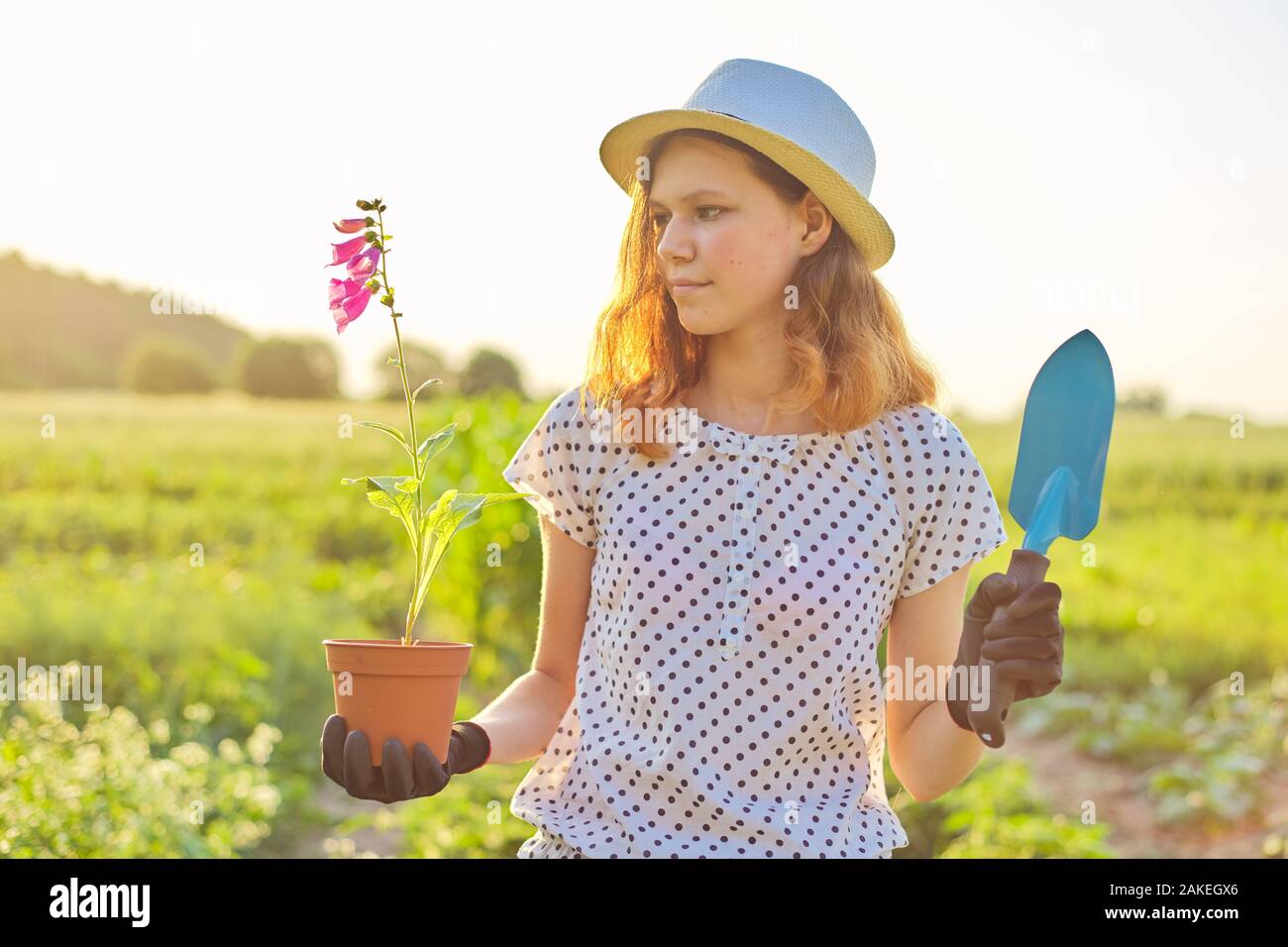 Girl in gloves with gardening tools planting flowers in garden Stock ...
