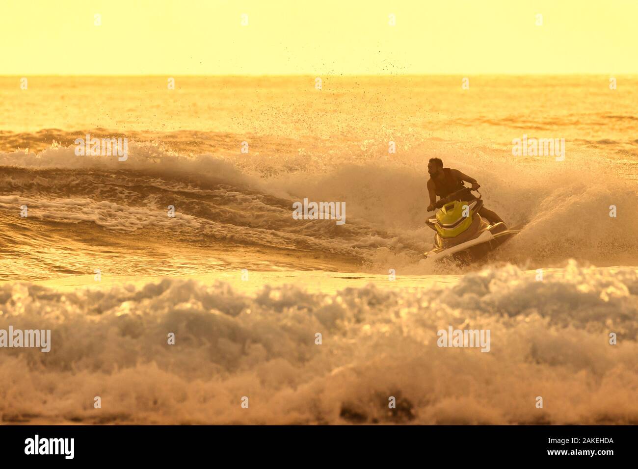 Silhouette of man riding a fast water motor bike through the waves on ...