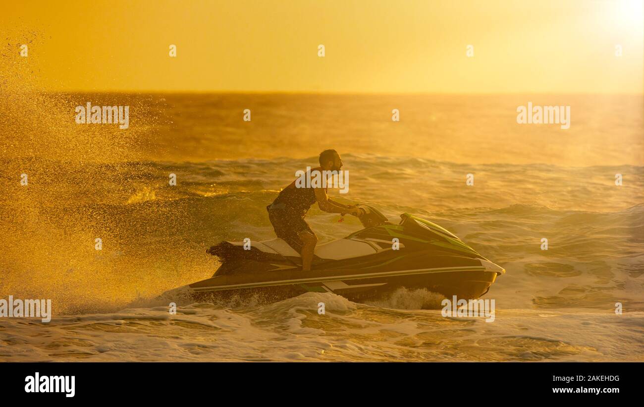 Silhouette of man riding a fast water motor bike through the waves on ...