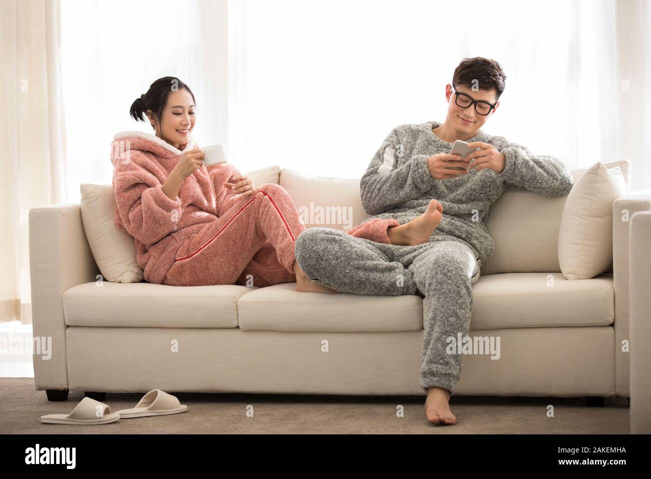 Happy young Chinese couple relaxing on sofa Stock Photo - Alamy