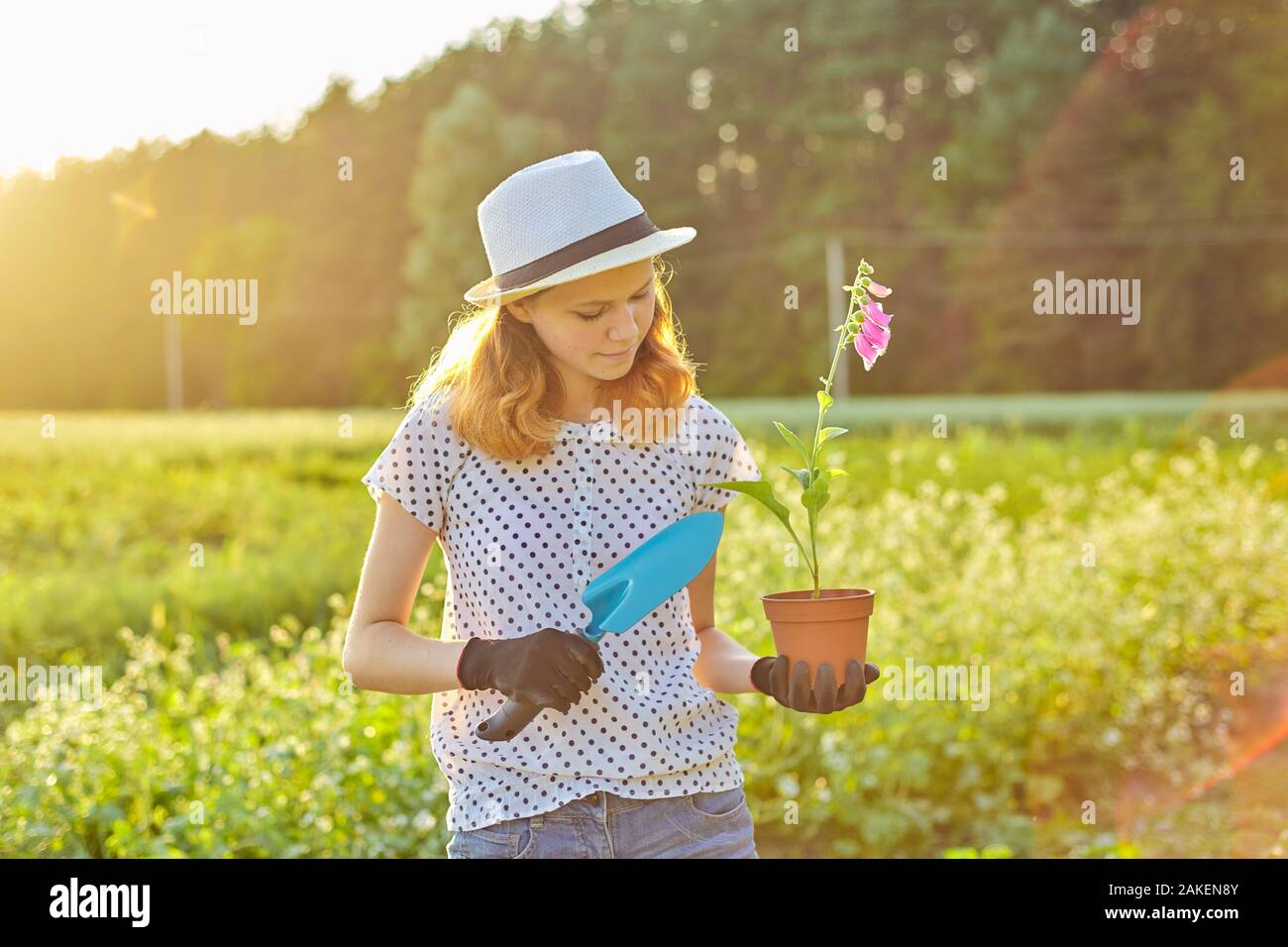 Girl in gloves with gardening tools planting flowers in garden Stock ...