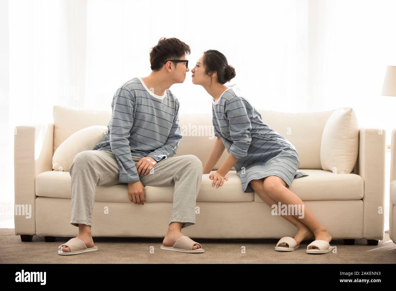 Happy young Chinese couple relaxing on sofa Stock Photo - Alamy