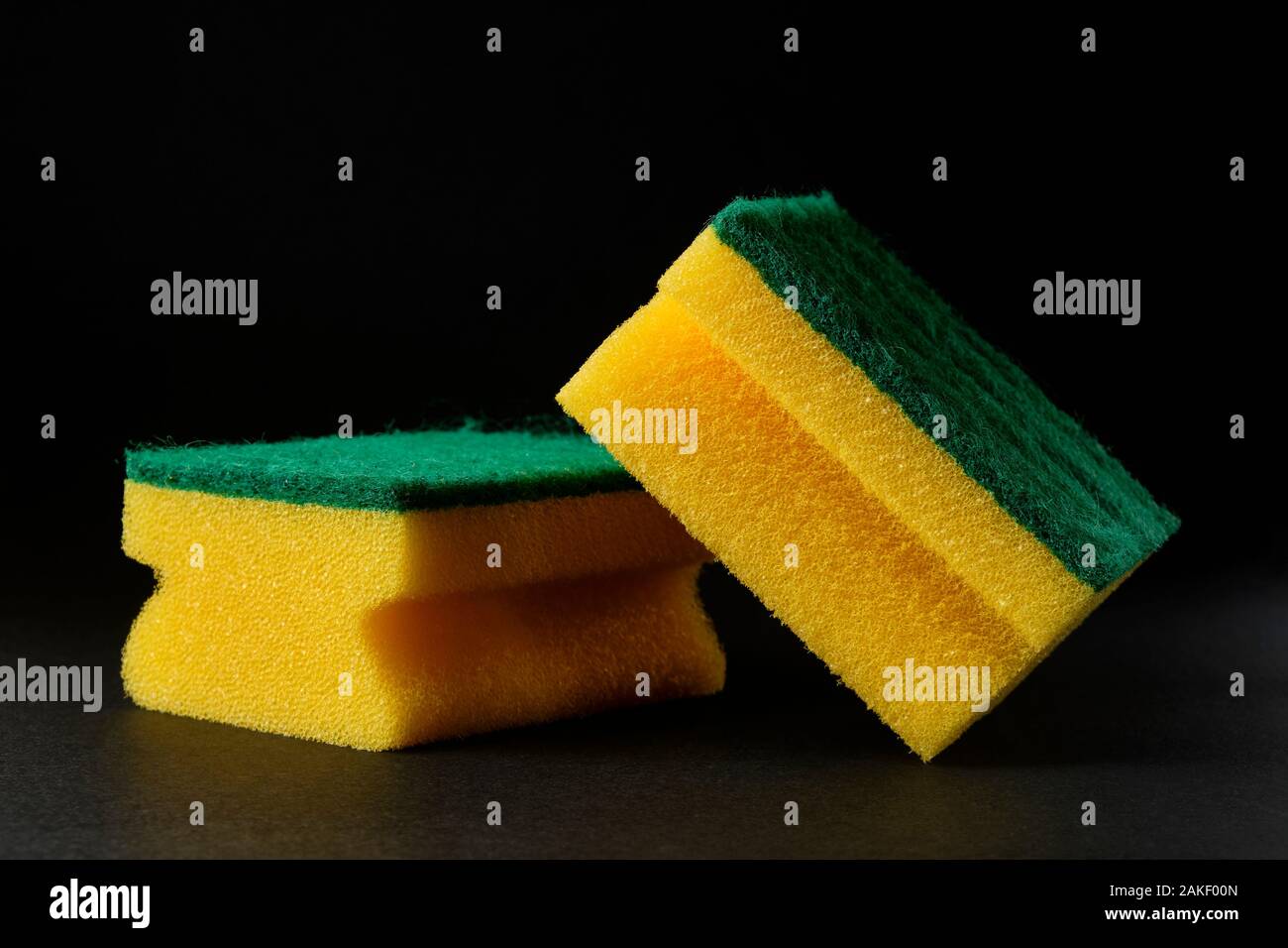 two new yellow sponges against black background Stock Photo - Alamy