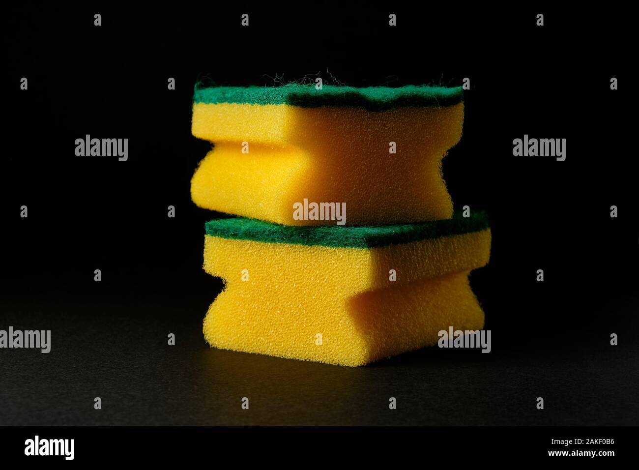 two new yellow sponges against black background Stock Photo - Alamy