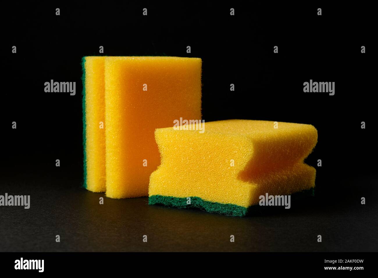 two new yellow sponges against black background Stock Photo - Alamy