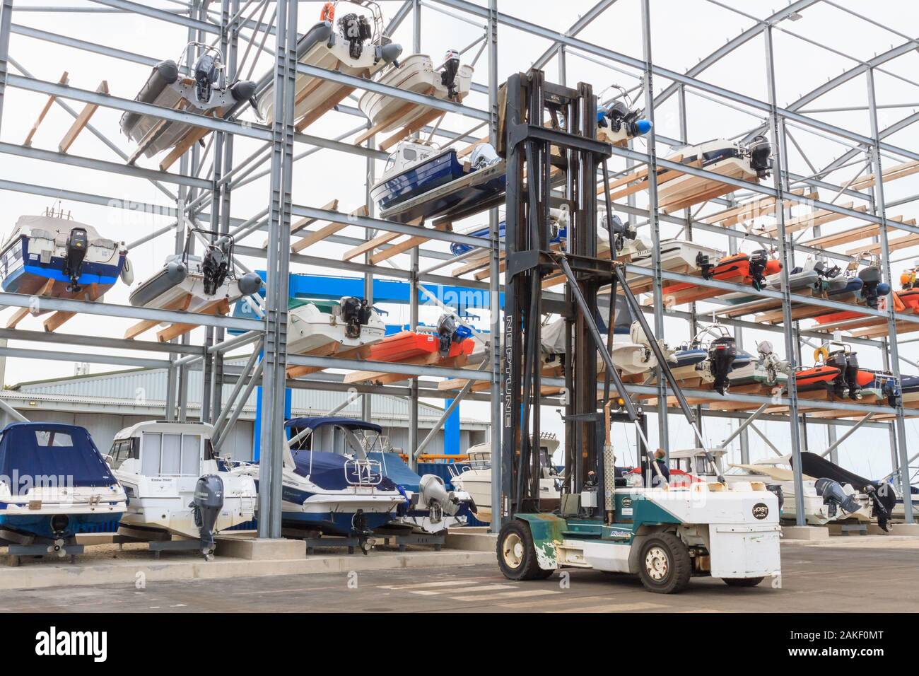 Heavy lift fork truck loading small pleasure craft into rack Stock ...