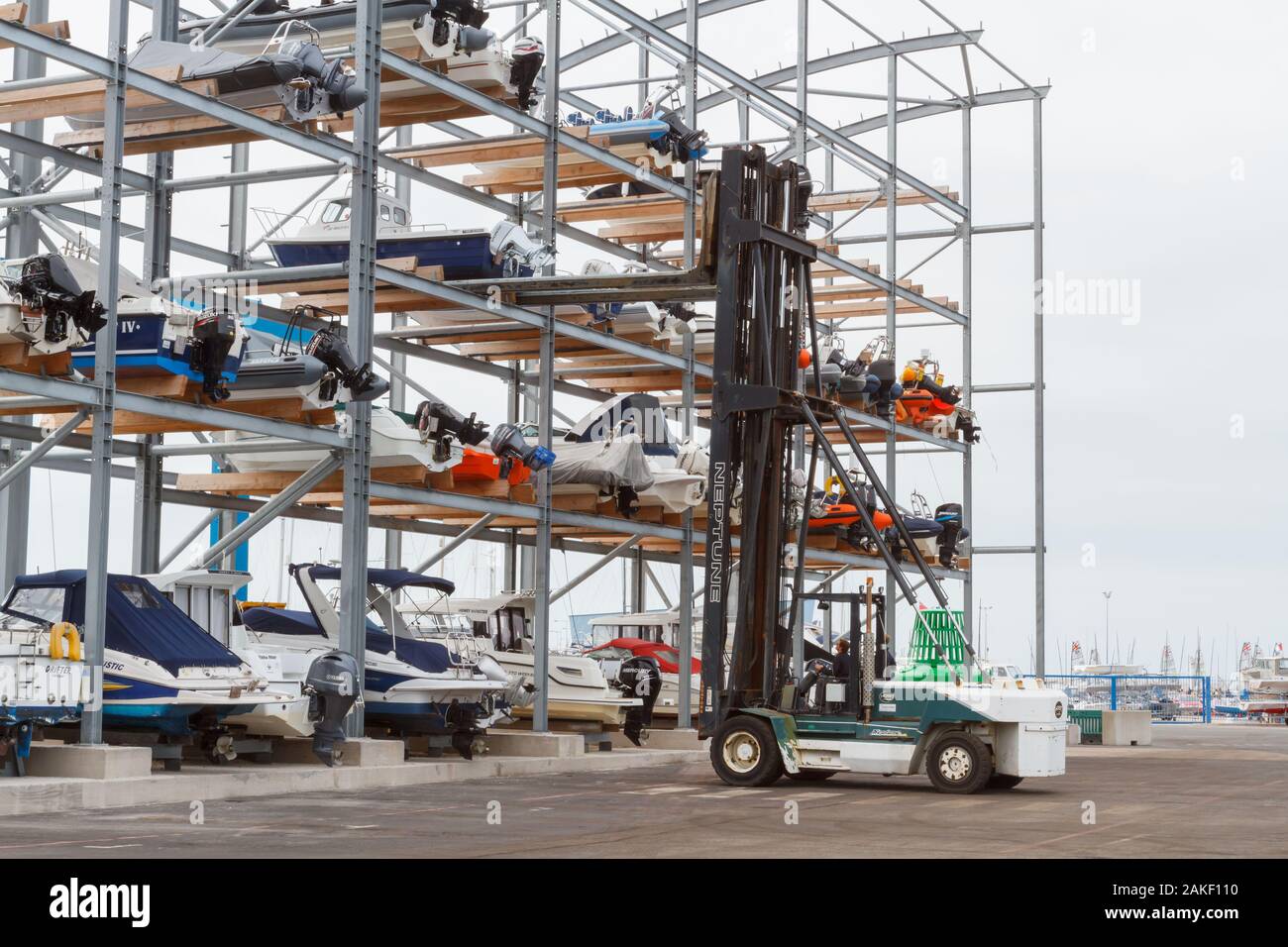 Heavy lift fork truck loading small pleasure craft into rack Stock ...
