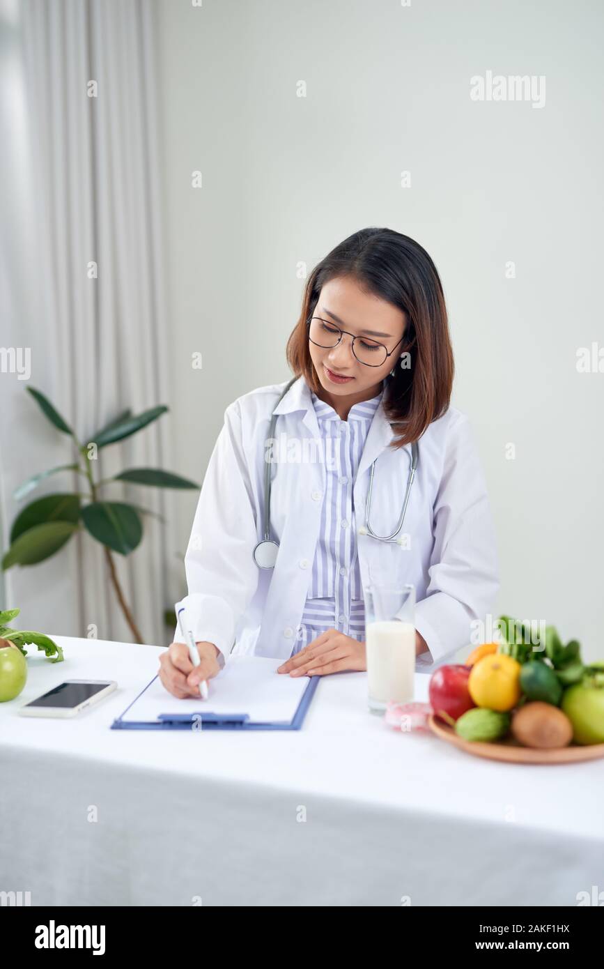 Asian Female nutritionist with fruits working at her desk. Health care ...