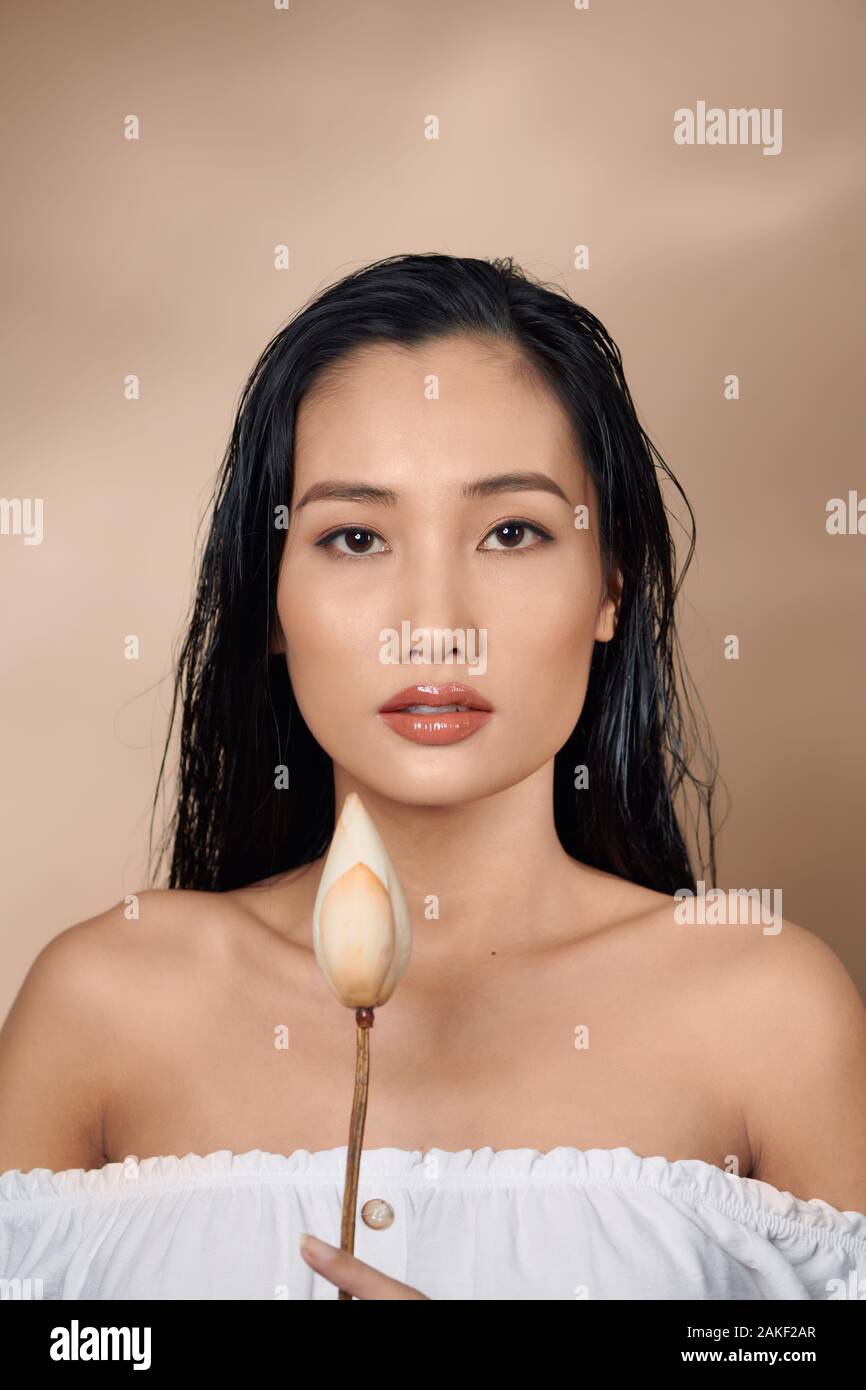 Young beautiful Asian women holding dried lotus buds on beige ...