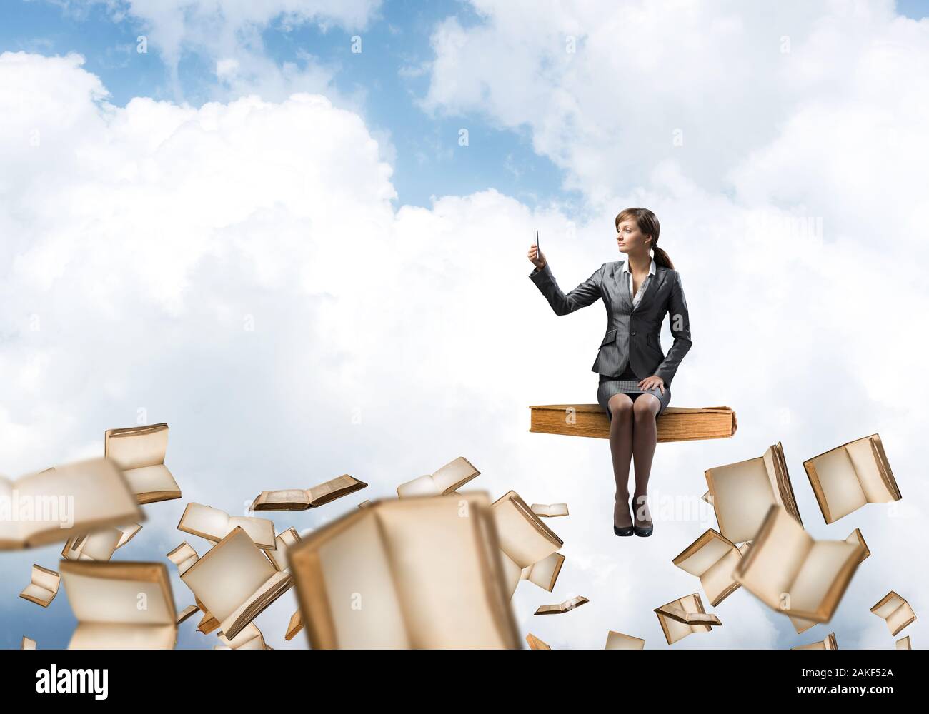 Attractive girl sitting on book and flying in sky Stock Photo - Alamy
